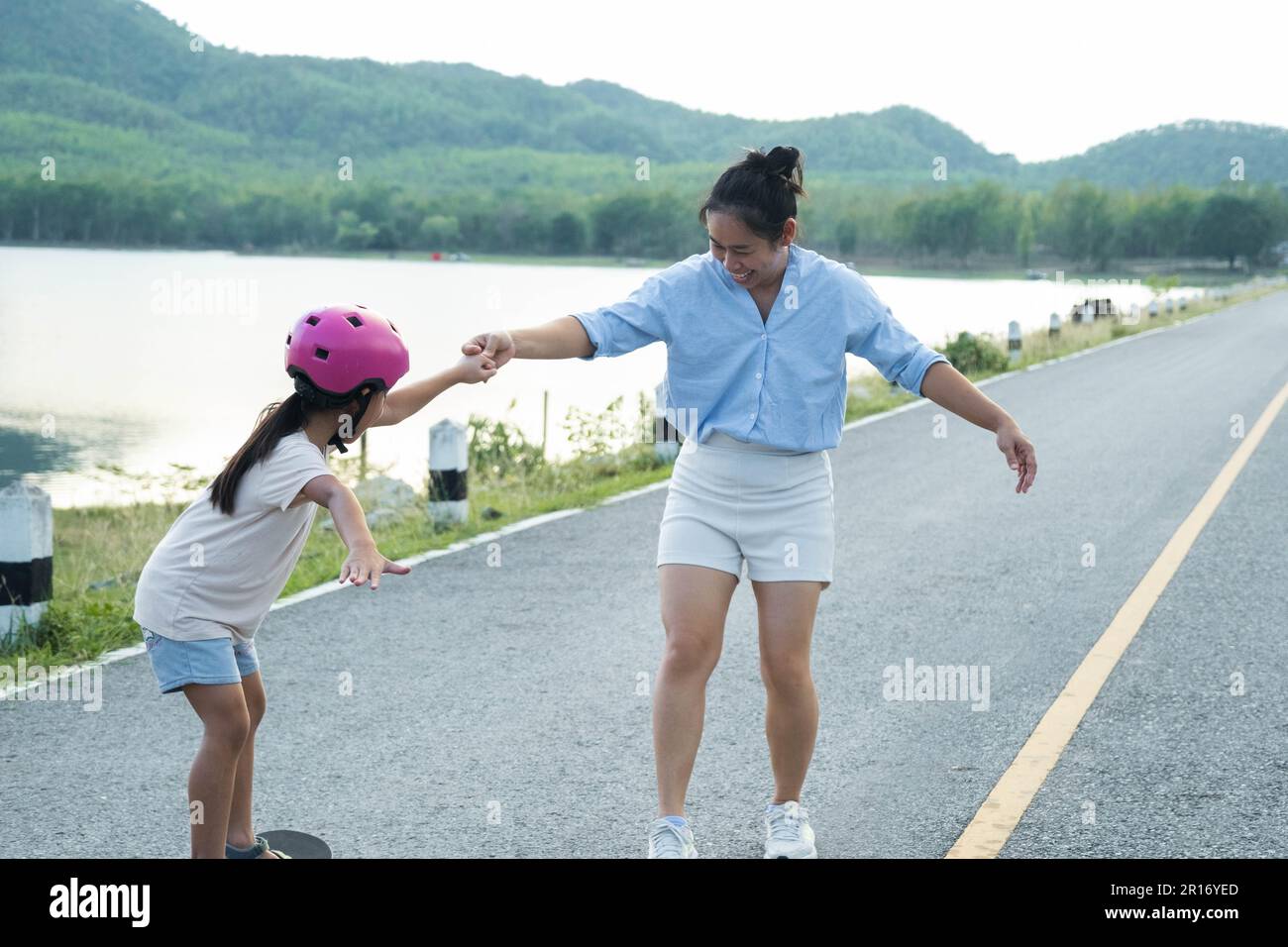 Mother teaching her daughter how to skateboard in the park. Child ...