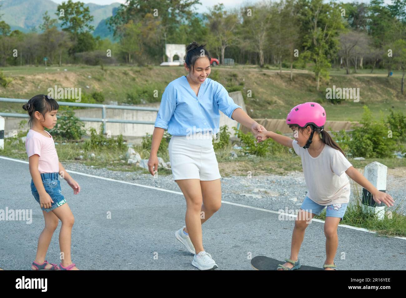 Mother teaching her daughter how to skateboard in the park. Child ...
