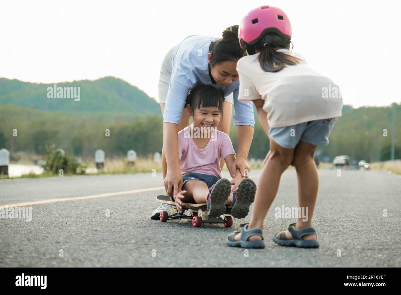 Mother teaching her daughter how to skateboard in the park. Child ...