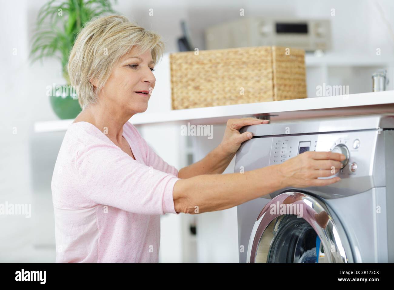senior woman loading washing machine at home Stock Photo - Alamy