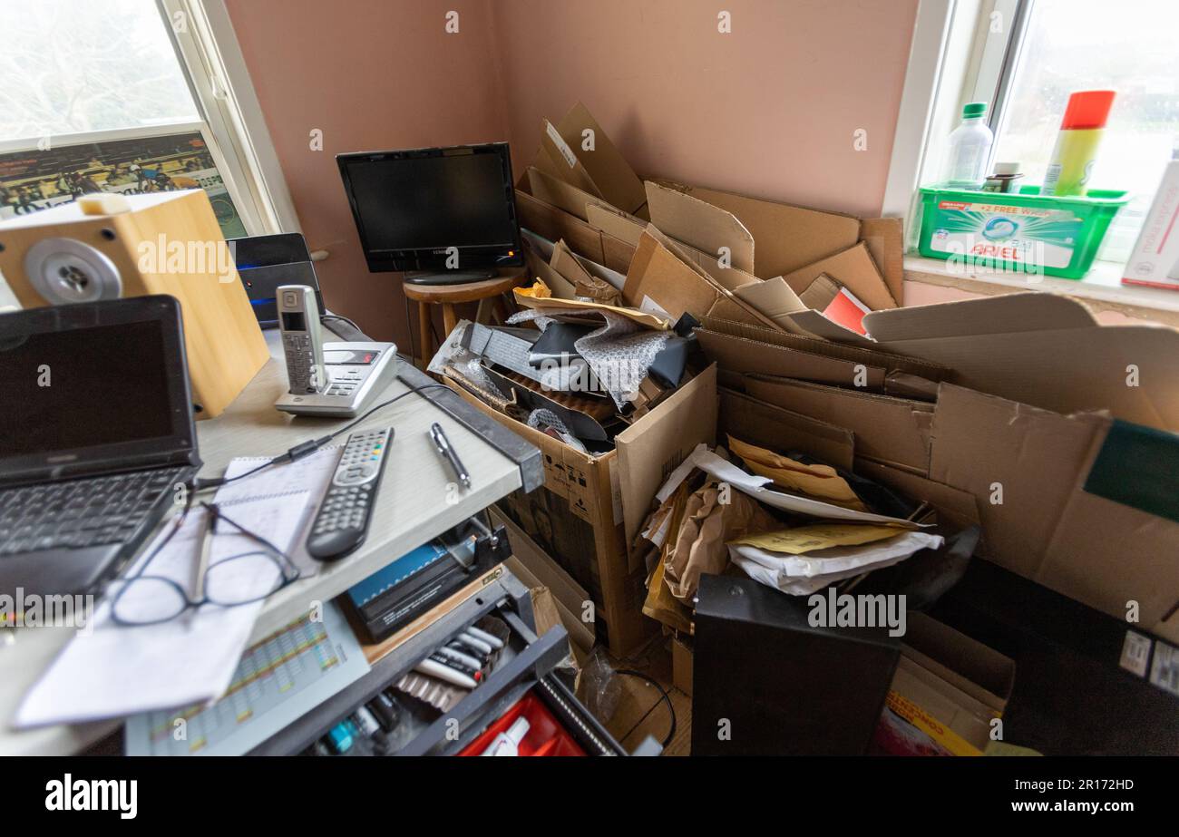 Heaps of cardboard packaging in a highly disorganised home workspace ...
