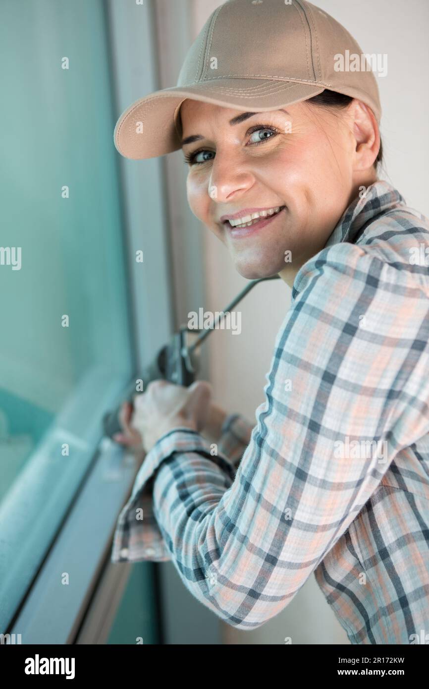 happy woman using silicone to fix a window Stock Photo - Alamy