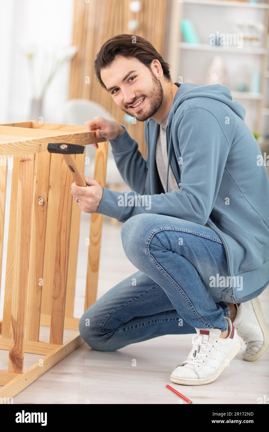 man putting together self assembly furniture in new home Stock Photo ...