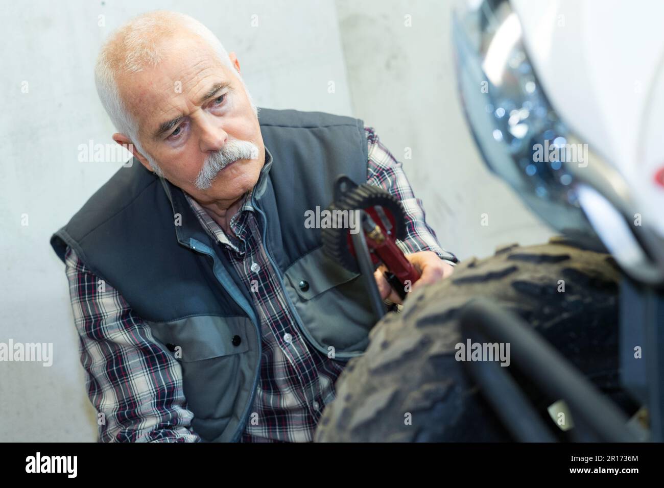 middle aged motorcycle mechanic is fixing a classic motorbike Stock ...
