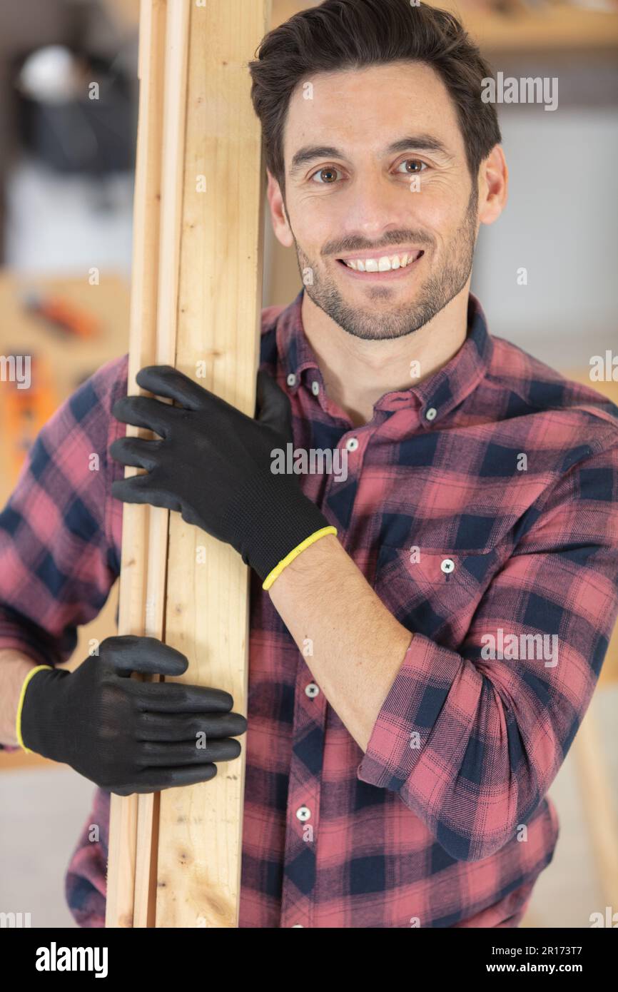 portrait of a smiling carpenter holding wood planks Stock Photo - Alamy