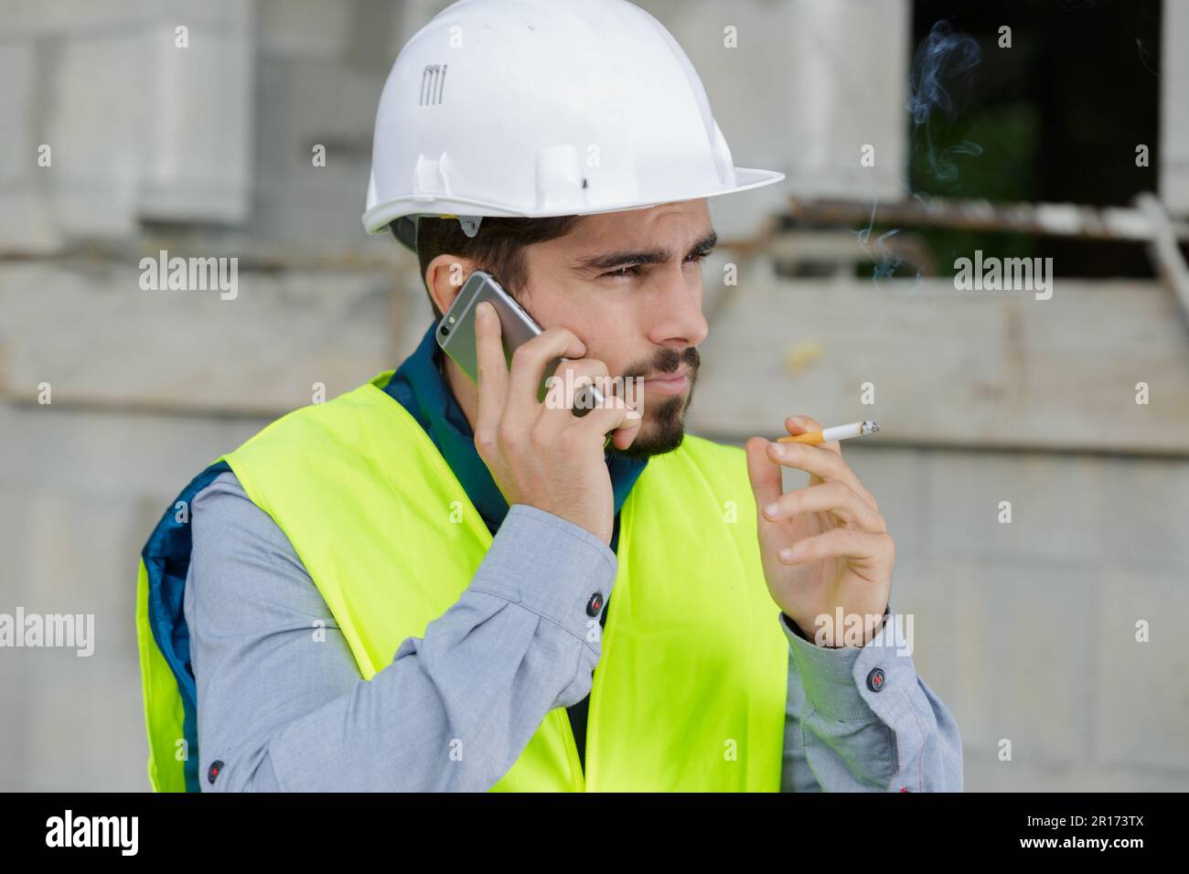 a young construction worker smoking on the phone Stock Photo - Alamy