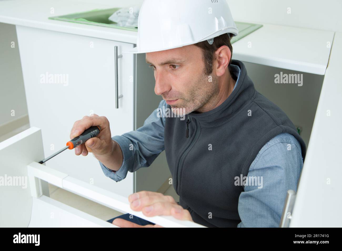 workman installing a fitted kitchen Stock Photo - Alamy
