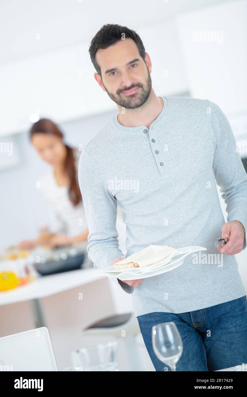 Young man laying the table Stock Photo - Alamy