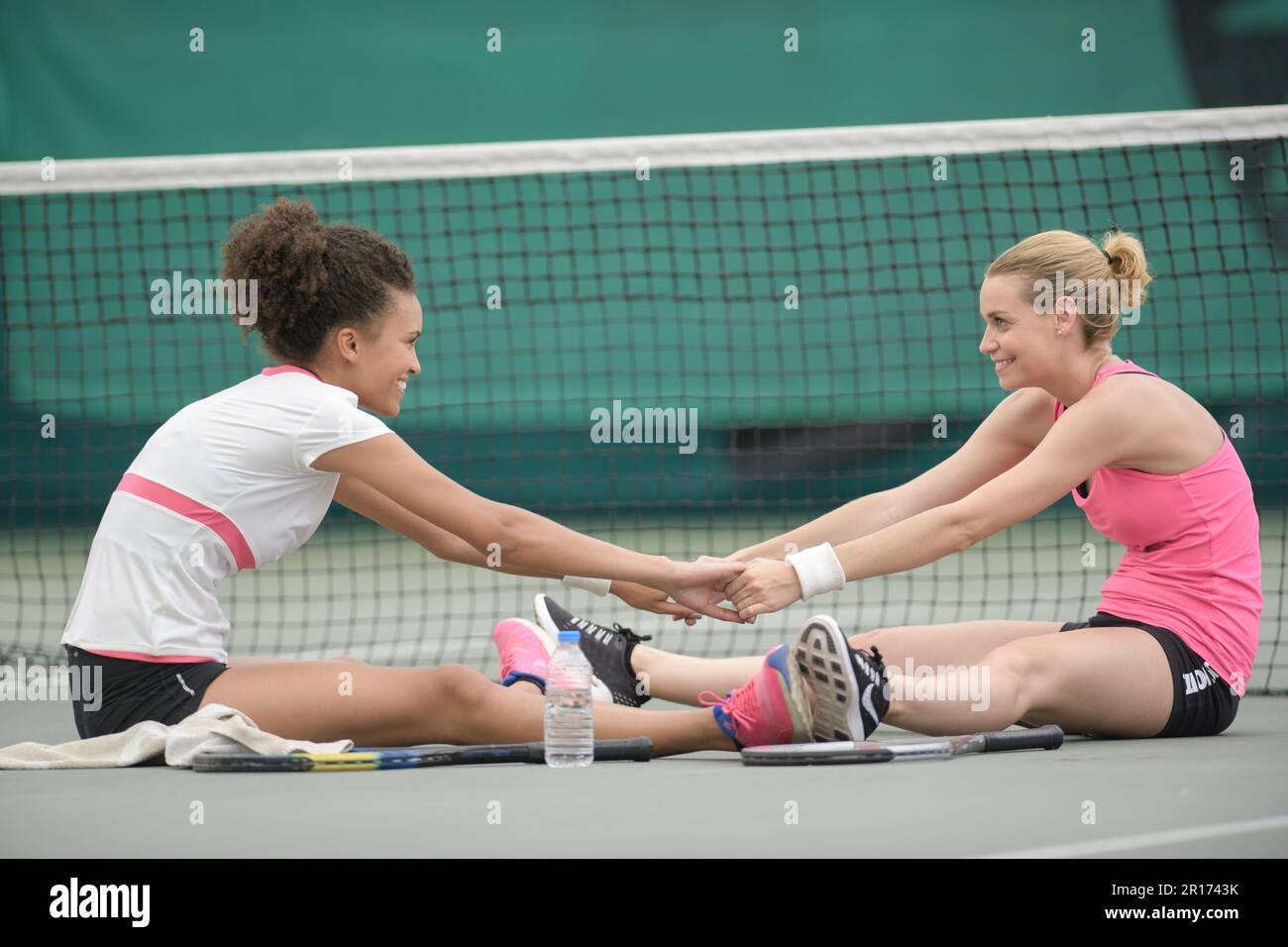 women on tennis court doing warming up stretches together Stock Photo ...