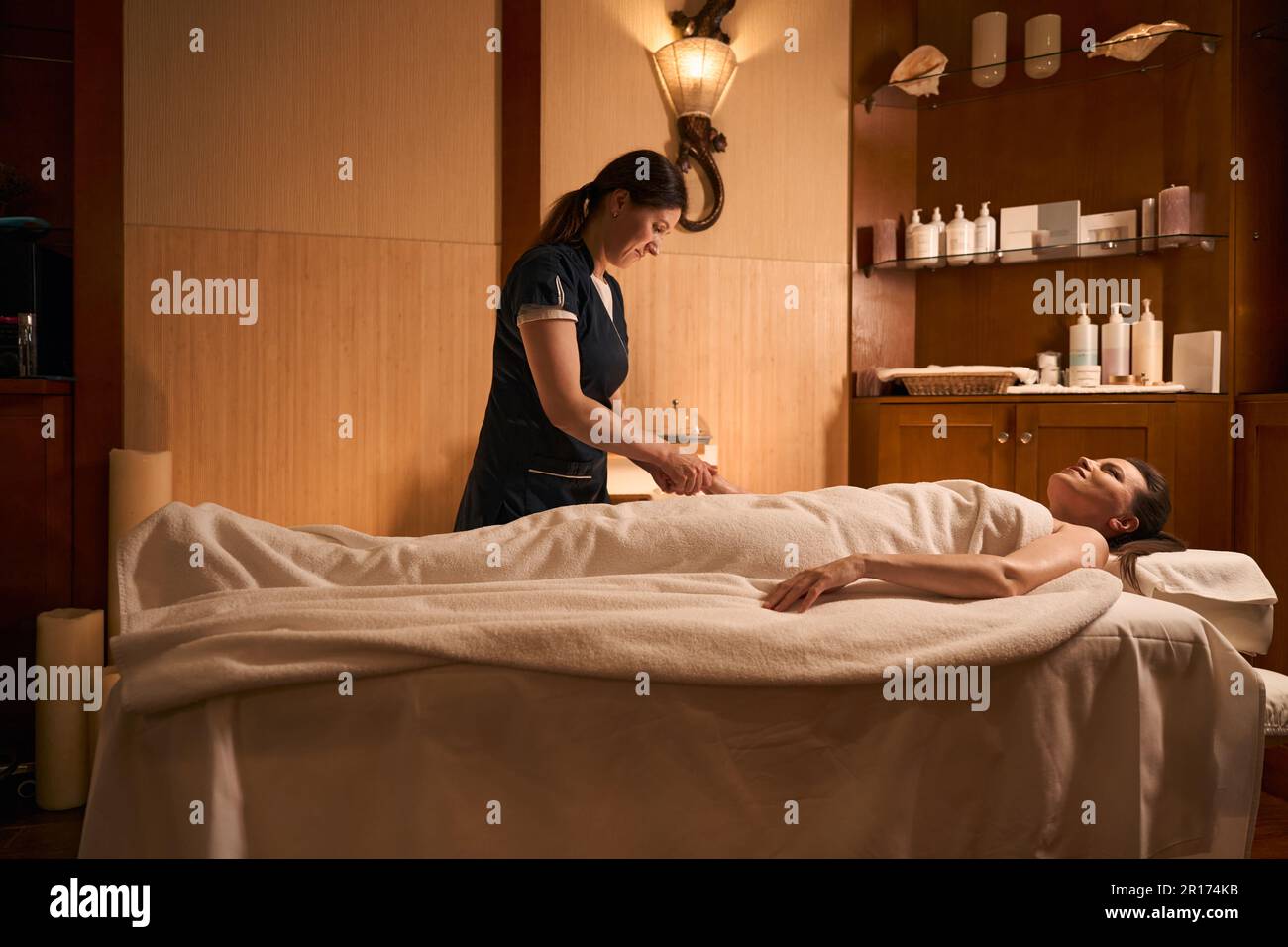 Concentrated wellness center massotherapist stretching woman wrist and ...