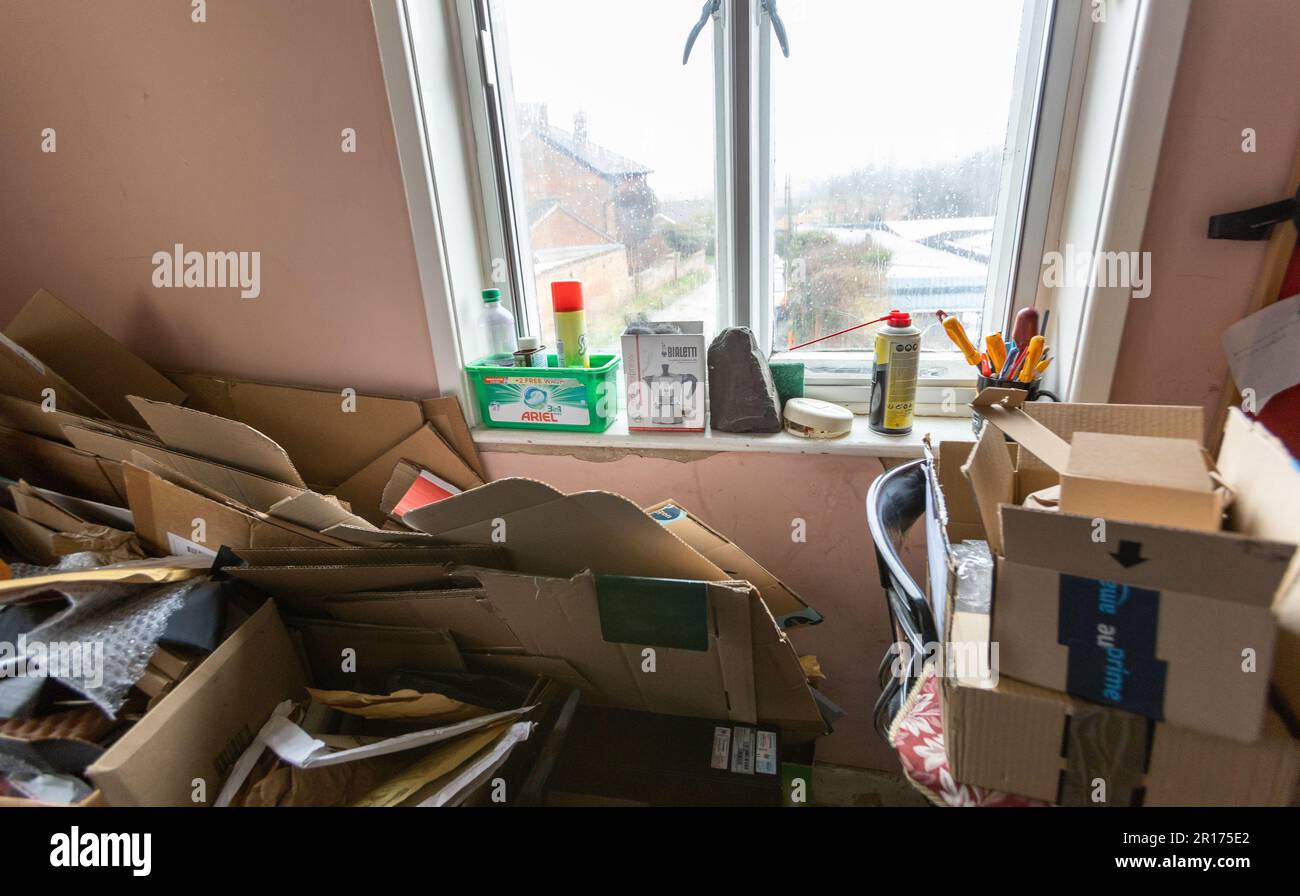 Heaps of cardboard packaging in a highly disorganised home workspace ...