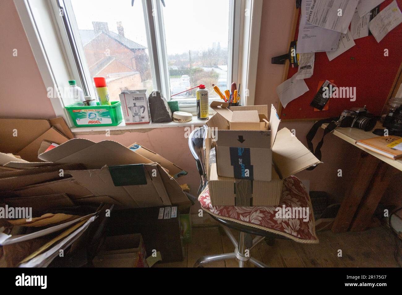 Heaps of cardboard packaging in a highly disorganised home workspace ...