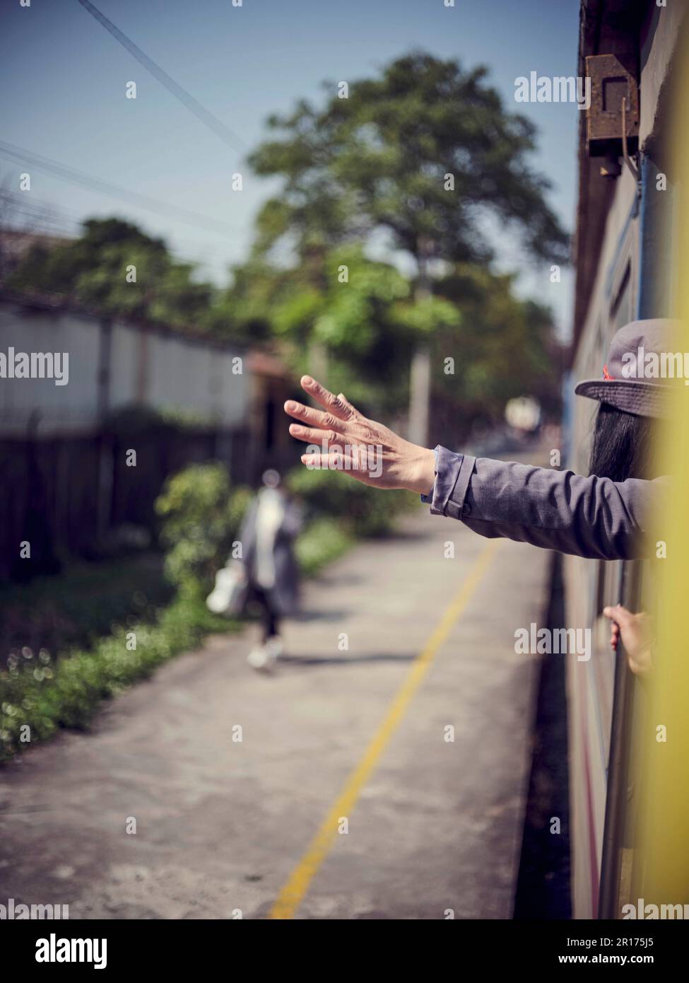 A person waving out the window of a train at a station Stock Photo - Alamy