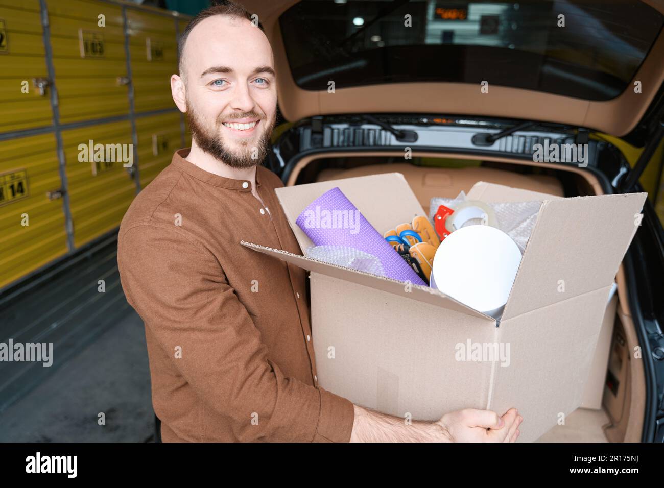 Happy young man holding a box with merchandise Stock Photo - Alamy