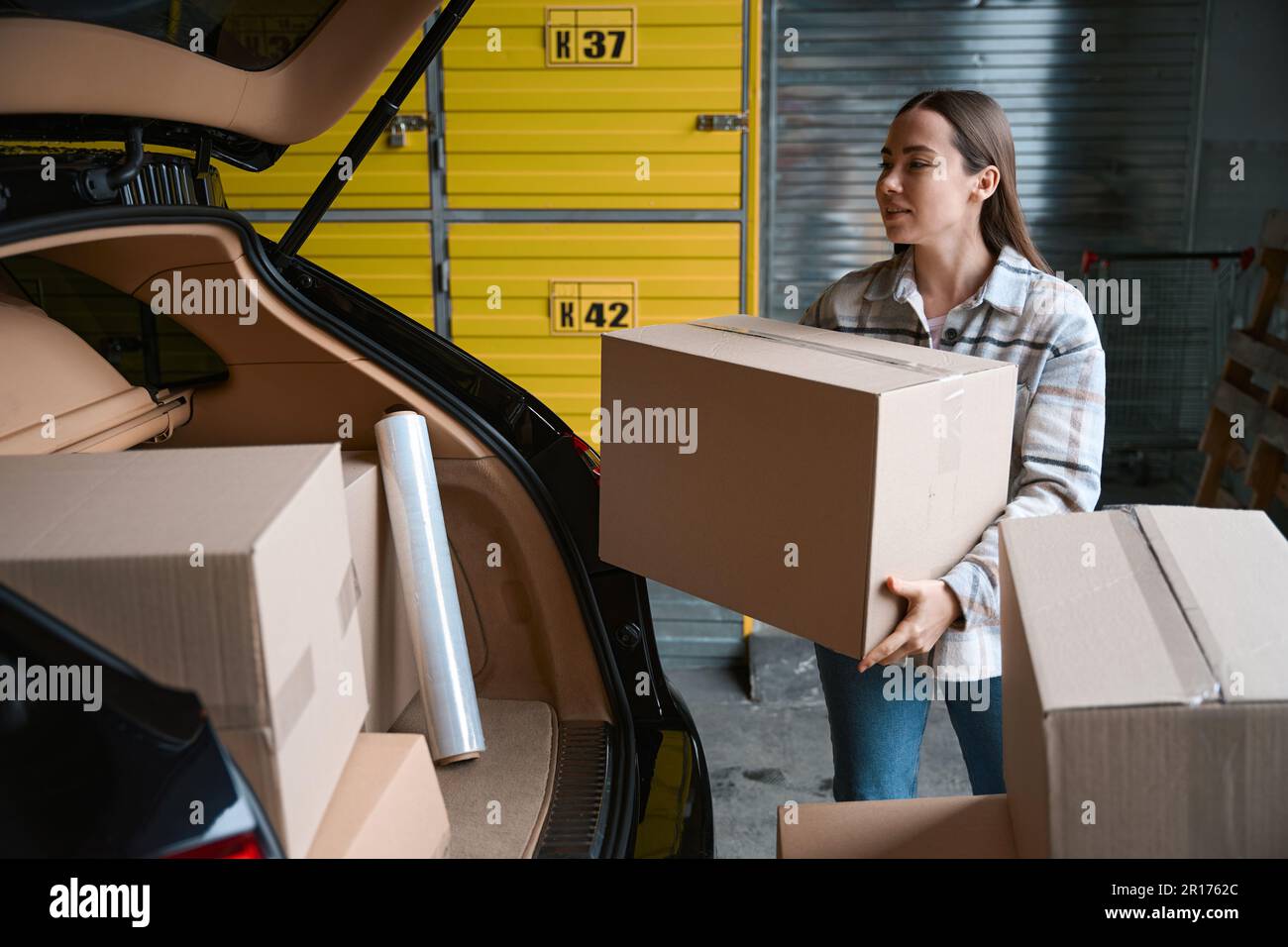Nice grown woman loading a box into the trunk Stock Photo - Alamy