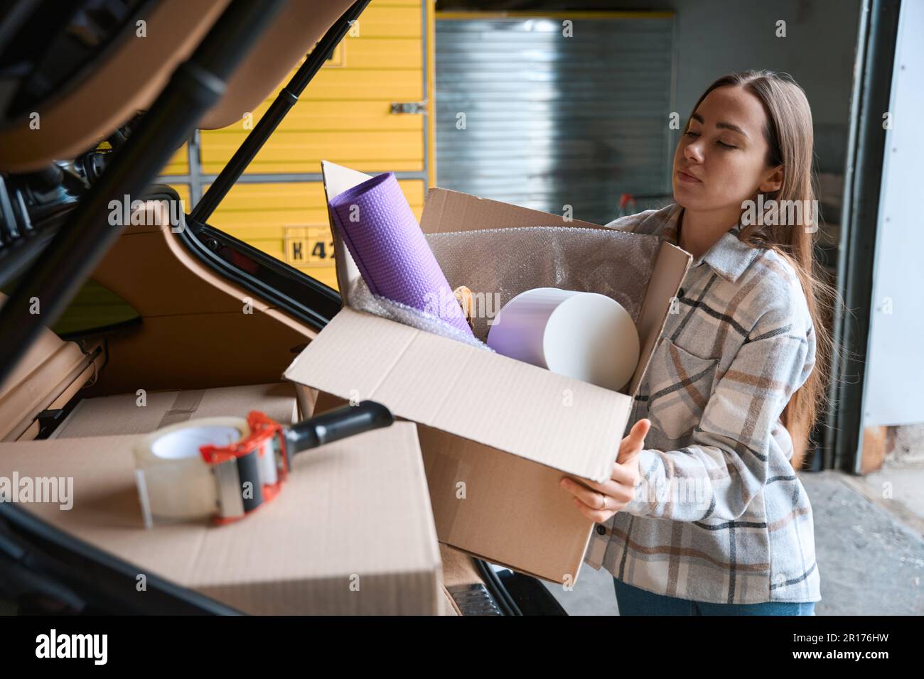 Beautiful woman taking a box of things from the trunk Stock Photo - Alamy