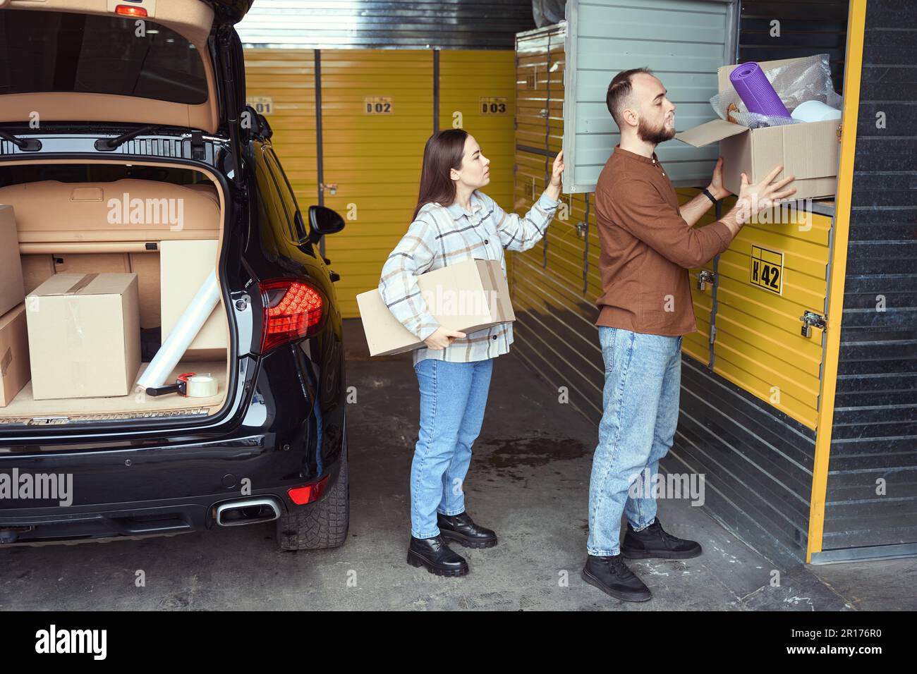 Young man and woman stacking merchandise for storage Stock Photo - Alamy