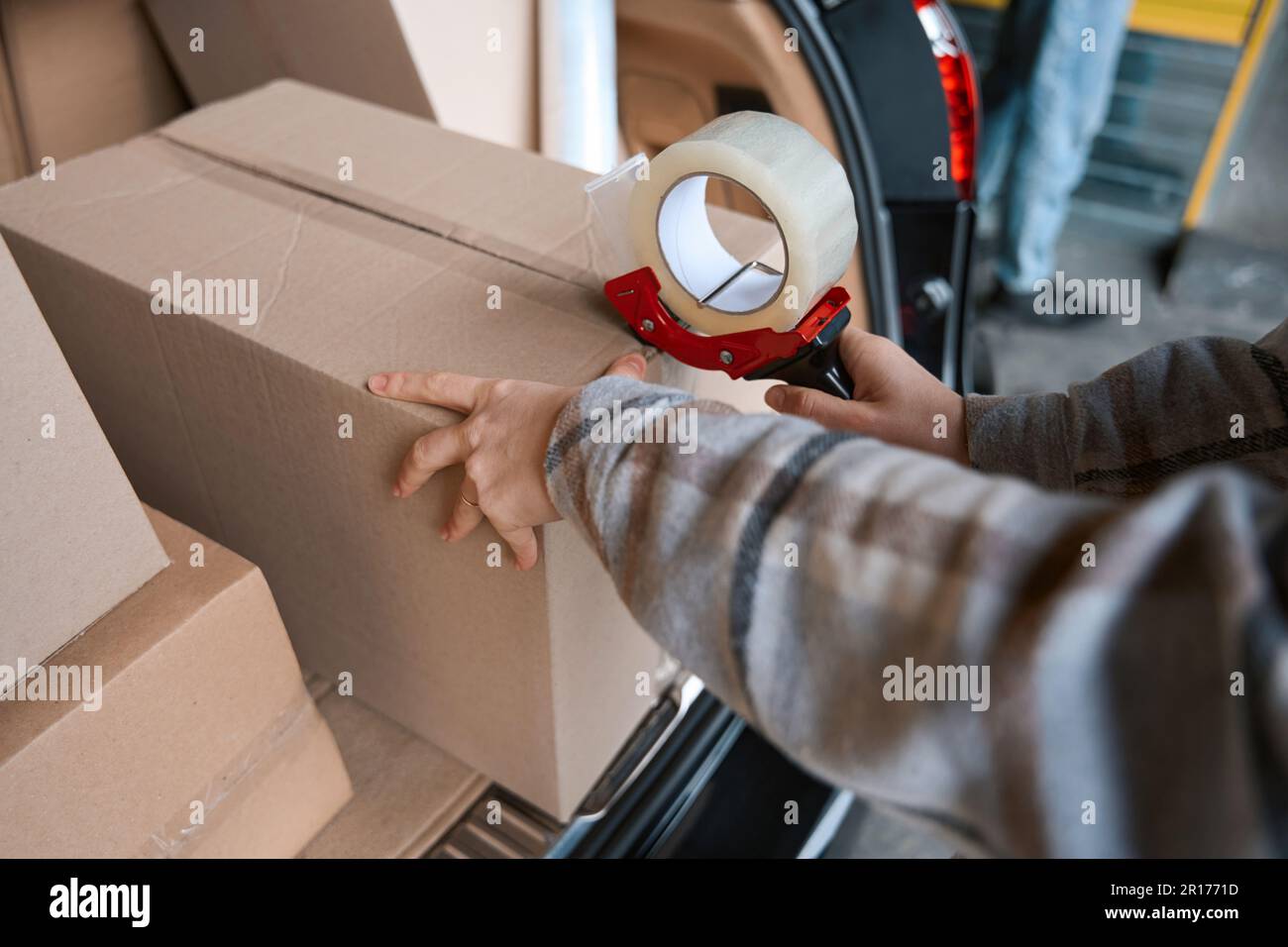 Packing a cardboard box in the trunk with duct tape Stock Photo - Alamy
