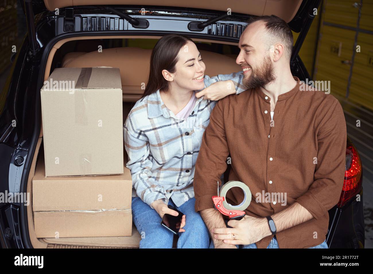 Two happy people sitting in the trunk of a car Stock Photo - Alamy