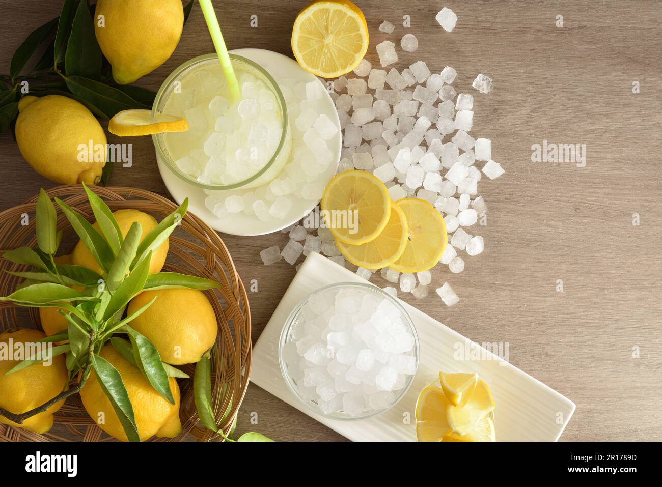 Lemonade with ice in a glass on a wooden kitchen bench and basket with ...