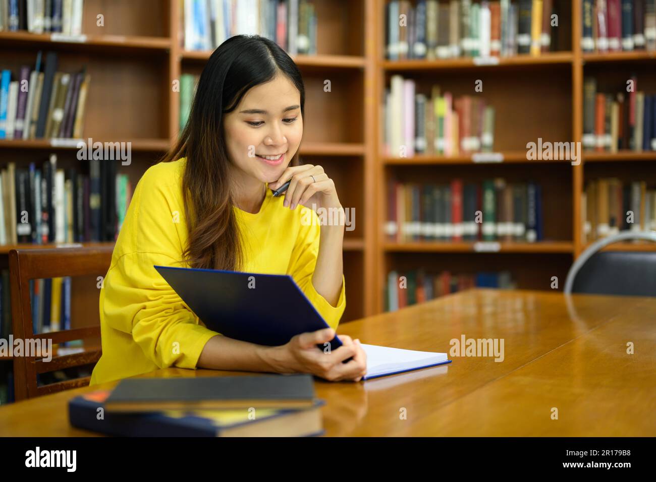 Beautiful asian woman sitting in library and reading text book during ...