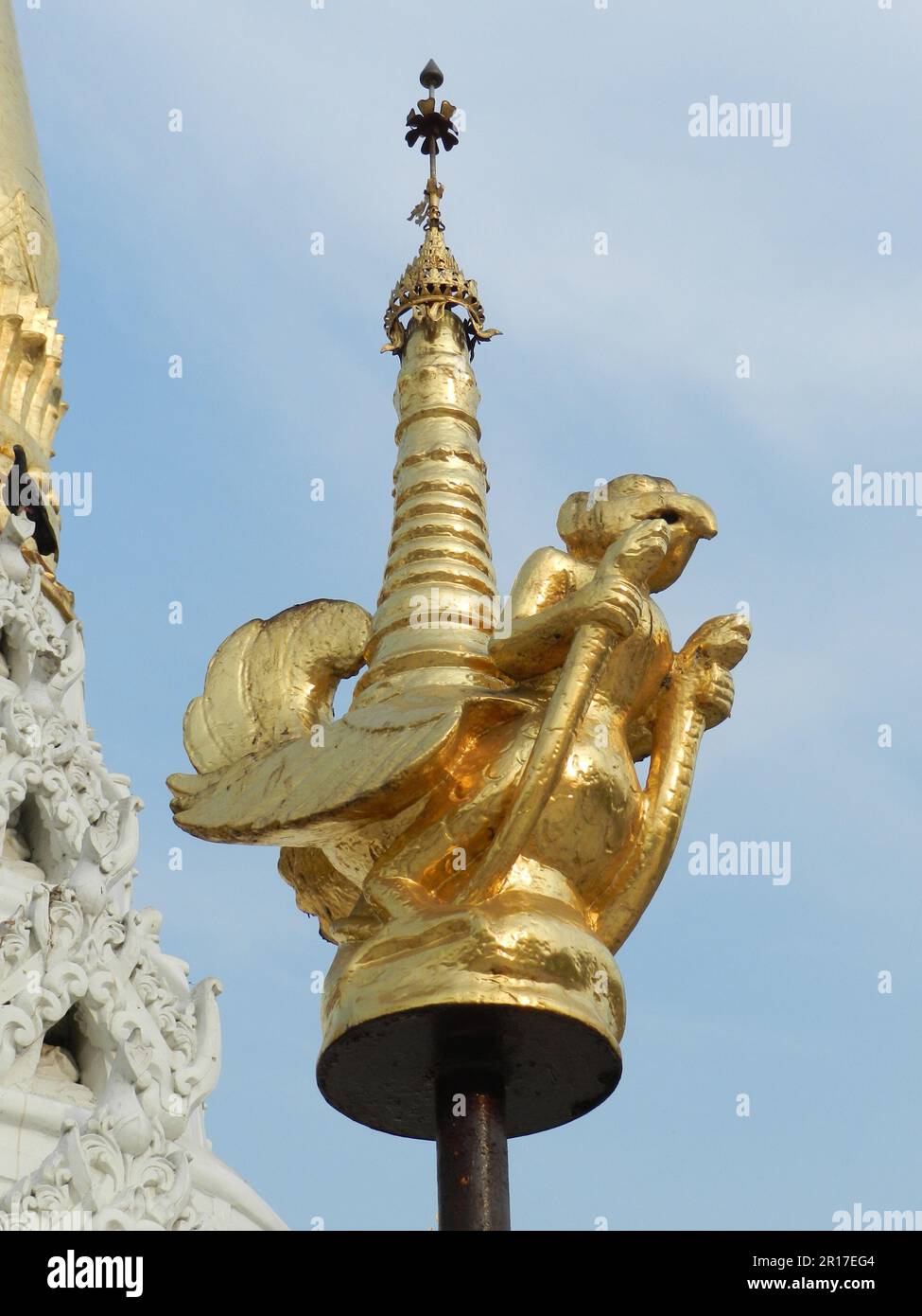 Myanmar, Yangon: gilded mythical figure holding two nagas, on a pole on ...