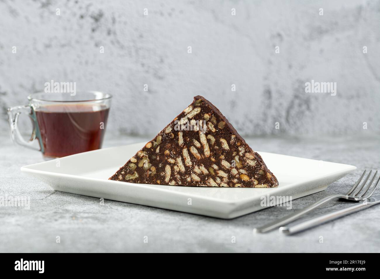 Chocolate mosaic cake with walnuts on a white porcelain plate on a ...