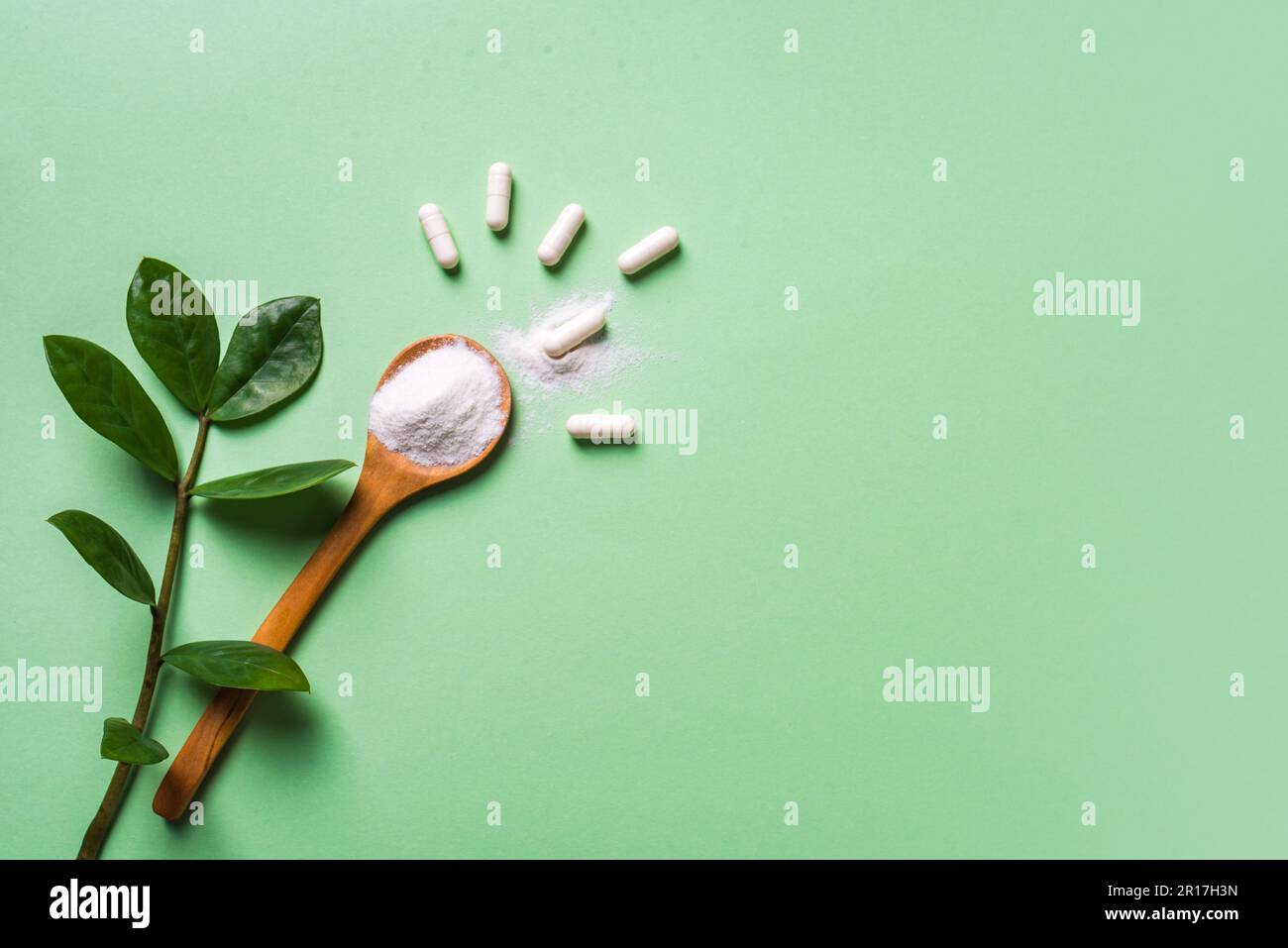 Collagen powder and capsules (pills) on green background, copy space ...