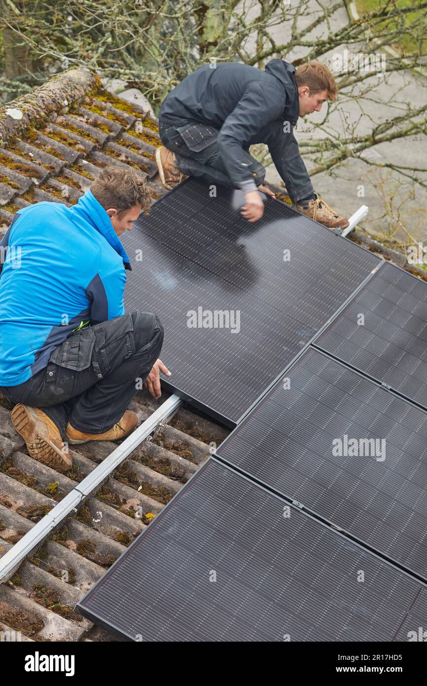 Photovoltaic solar panels being fitted to a residental roof in England ...
