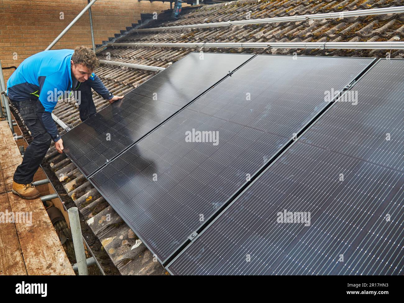 Photovoltaic solar panels being fitted to a residental roof in England ...