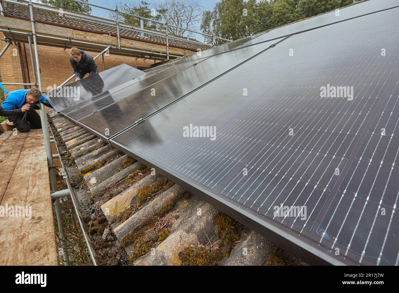 Photovoltaic solar panels being fitted to a residental roof in England ...