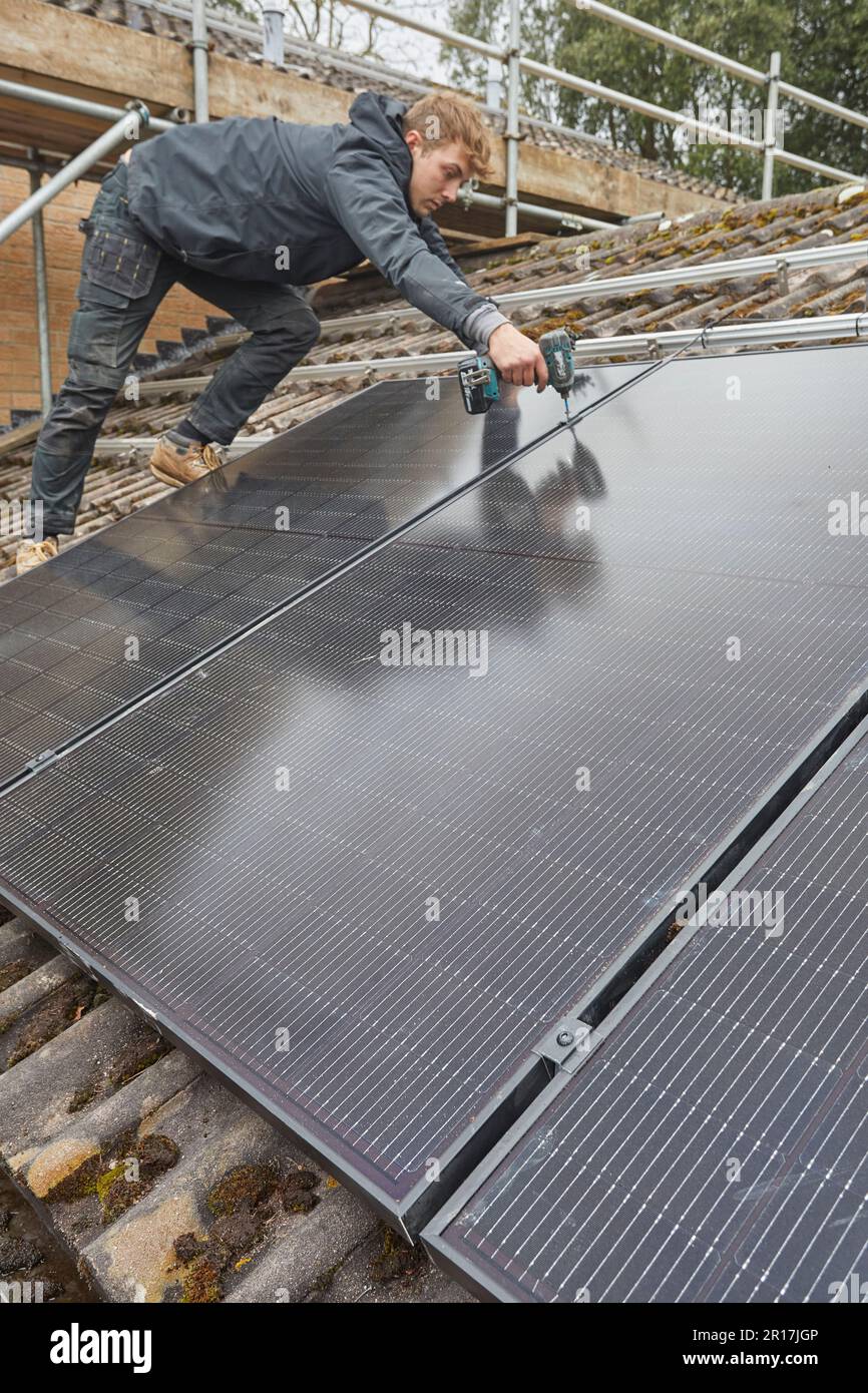 Photovoltaic solar panels being fitted to a residental roof in England ...