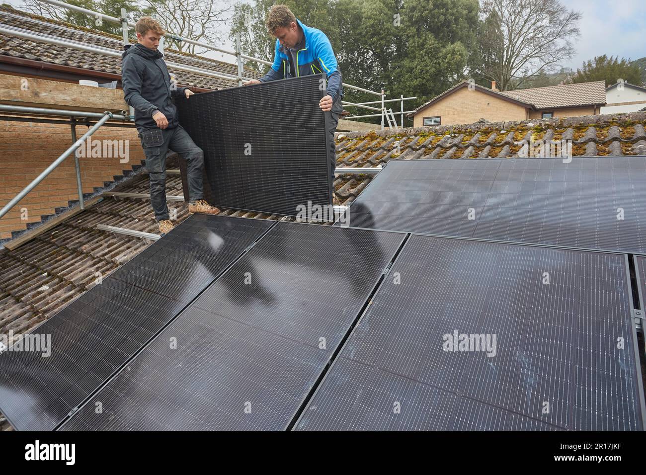 Photovoltaic solar panels being fitted to a residental roof in England ...
