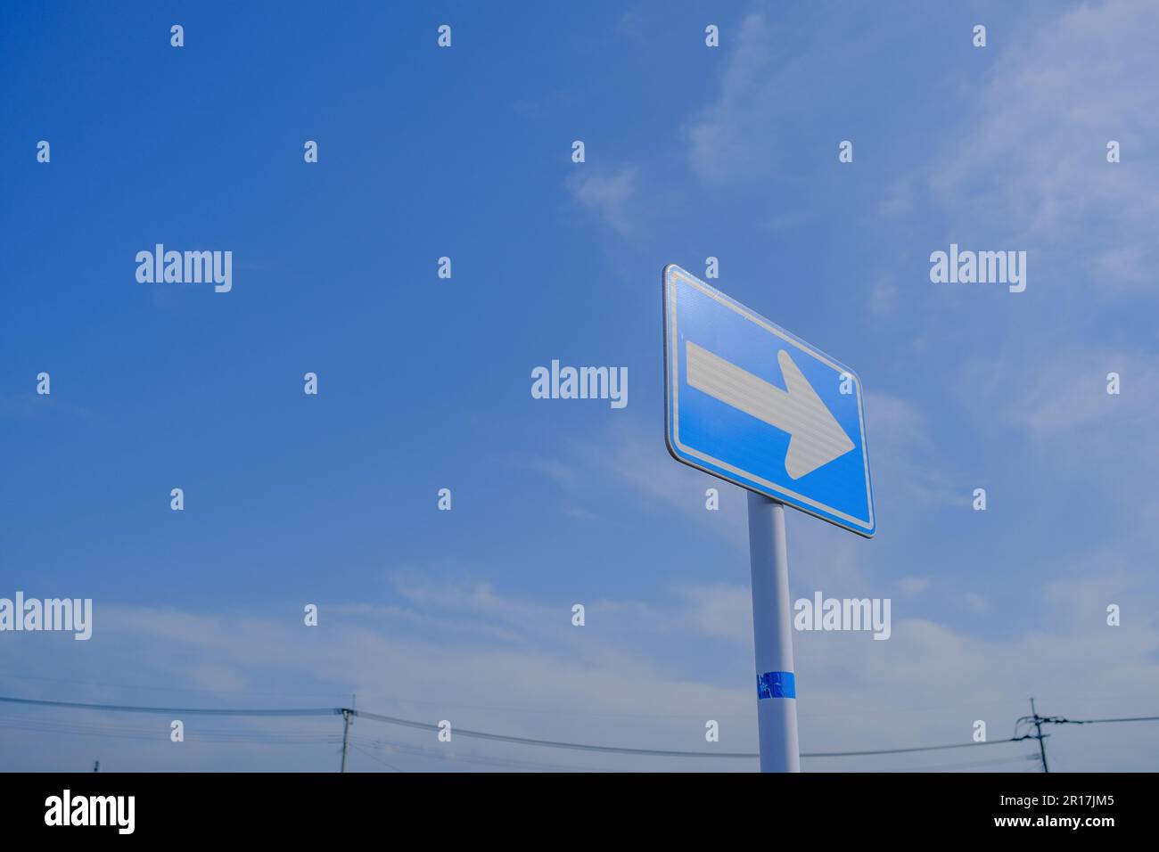 Blue One-Way Traffic Sign against a Blue Sky with some White Clouds ...