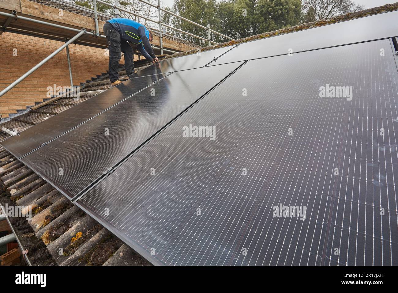 Photovoltaic solar panels being fitted to a residental roof in England ...