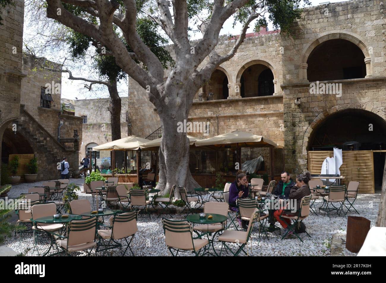 Greece, Island of Rhodes: open air cafe under a shady tree by the Inn ...