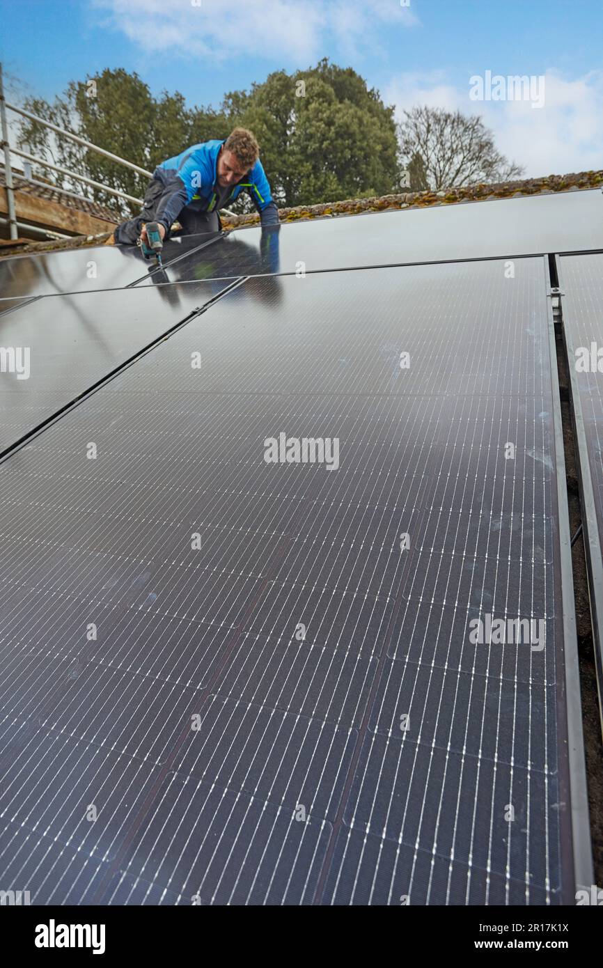 Photovoltaic solar panels being fitted to a residental roof in England ...