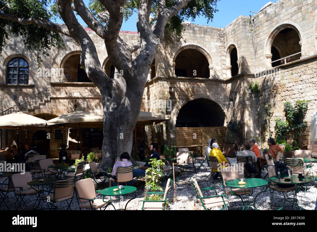Greece, Island of Rhodes: open air cafe under a shady tree by the Inn ...