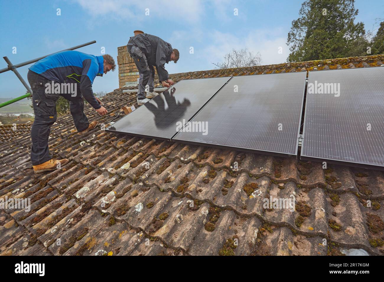 Photovoltaic solar panels being fitted to a residental roof in England ...