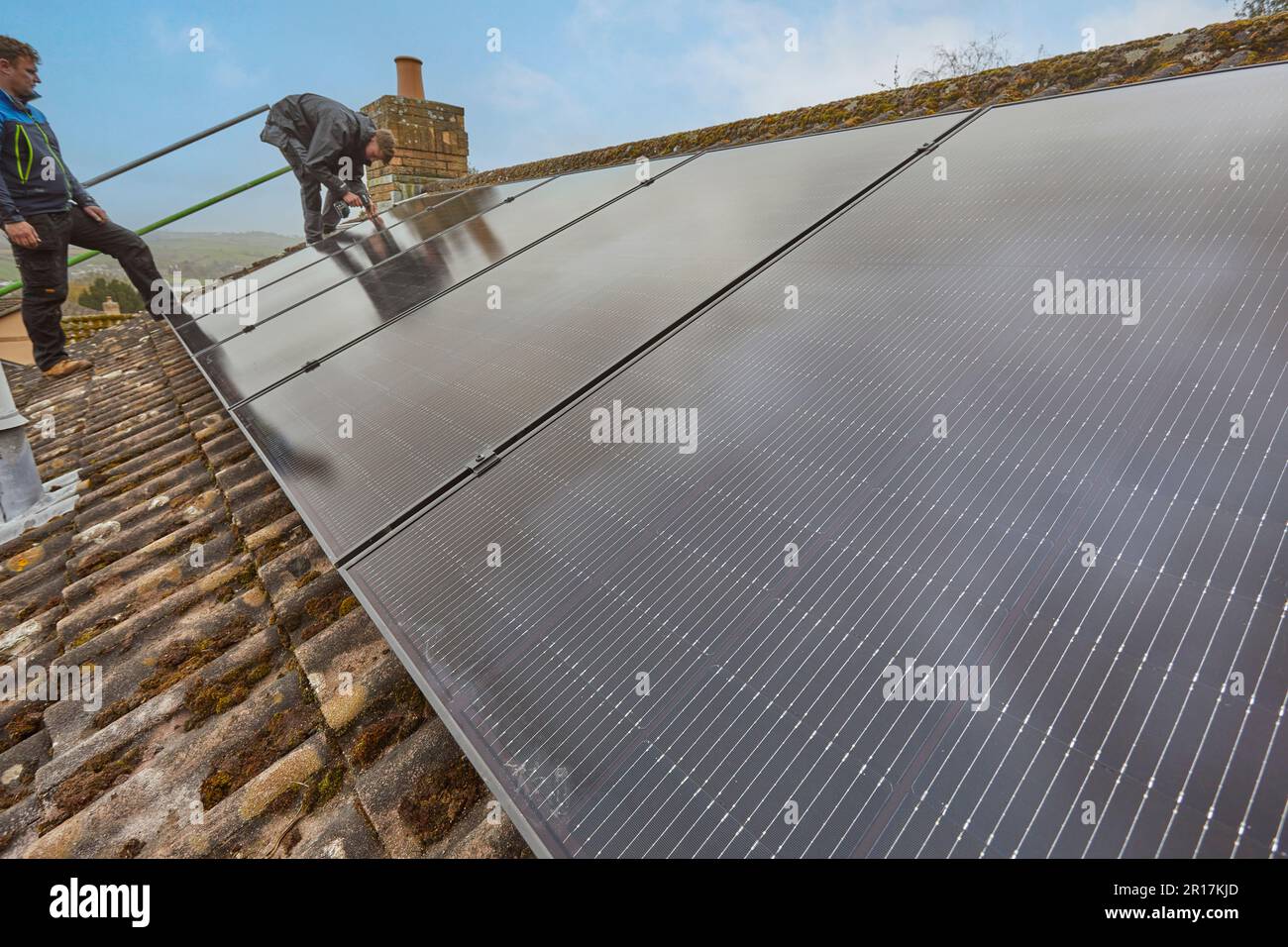 Photovoltaic solar panels being fitted to a residental roof in England ...