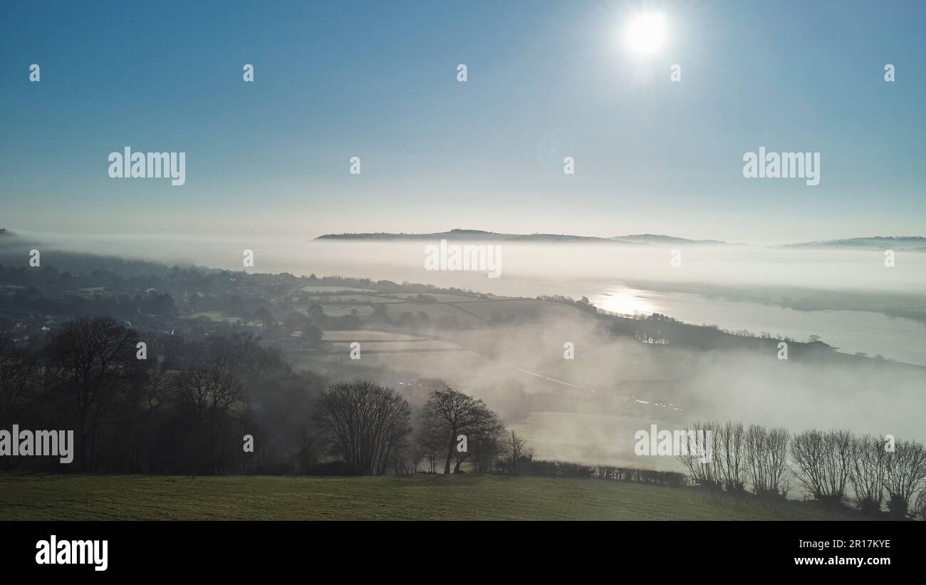 A calm early morning view of a mist-filled river valley: the estuary of ...