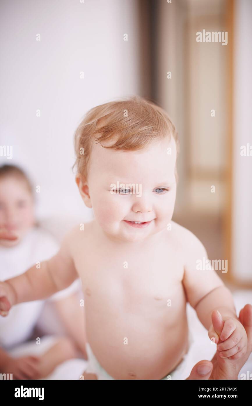 Baby steps...a baby girl standing up with the assistance of her parents ...
