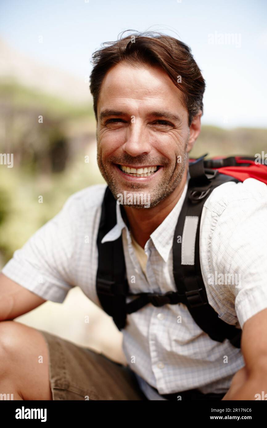 I love taking trips into nature. Handsome male hiker smiling while ...