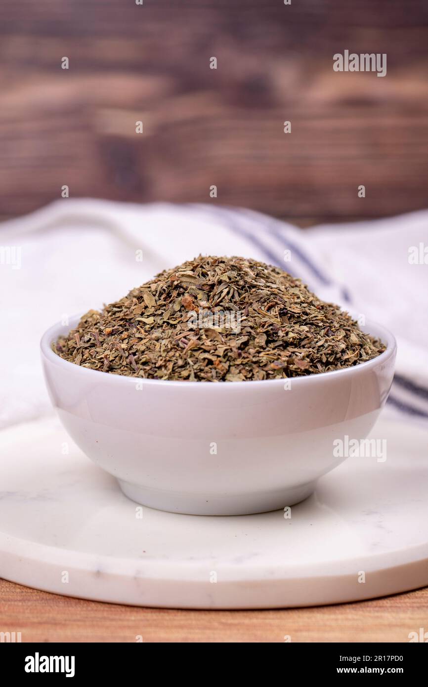 Dried crushed basil on wooden background. Dried ground basil powder ...
