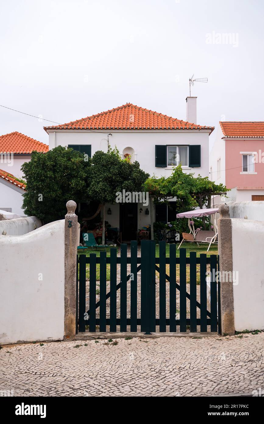 White villa with tiled roof and green wooden gate in front Stock Photo ...