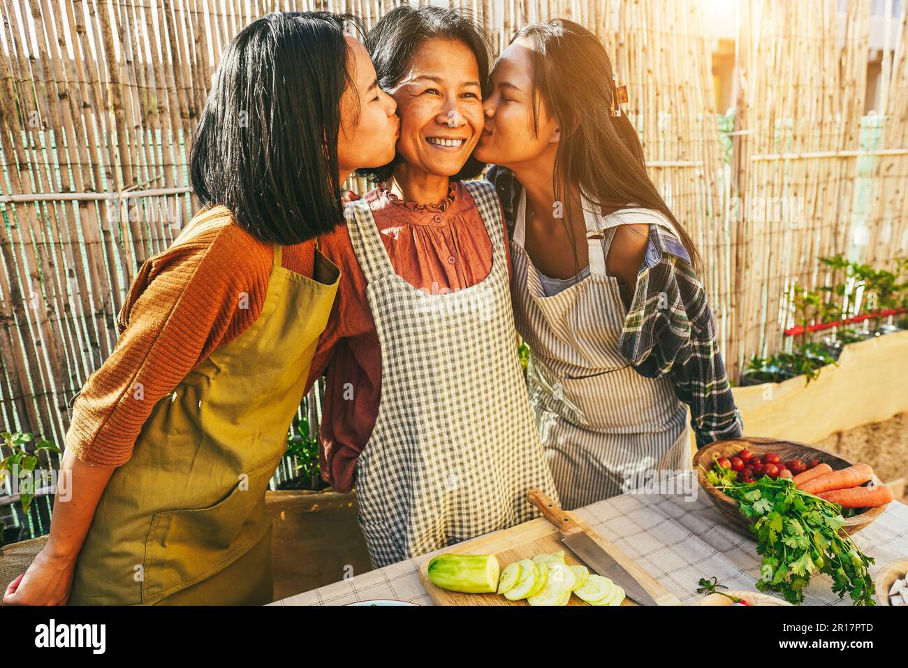 Happy asian mother having fun with her daughters while cooking at home ...