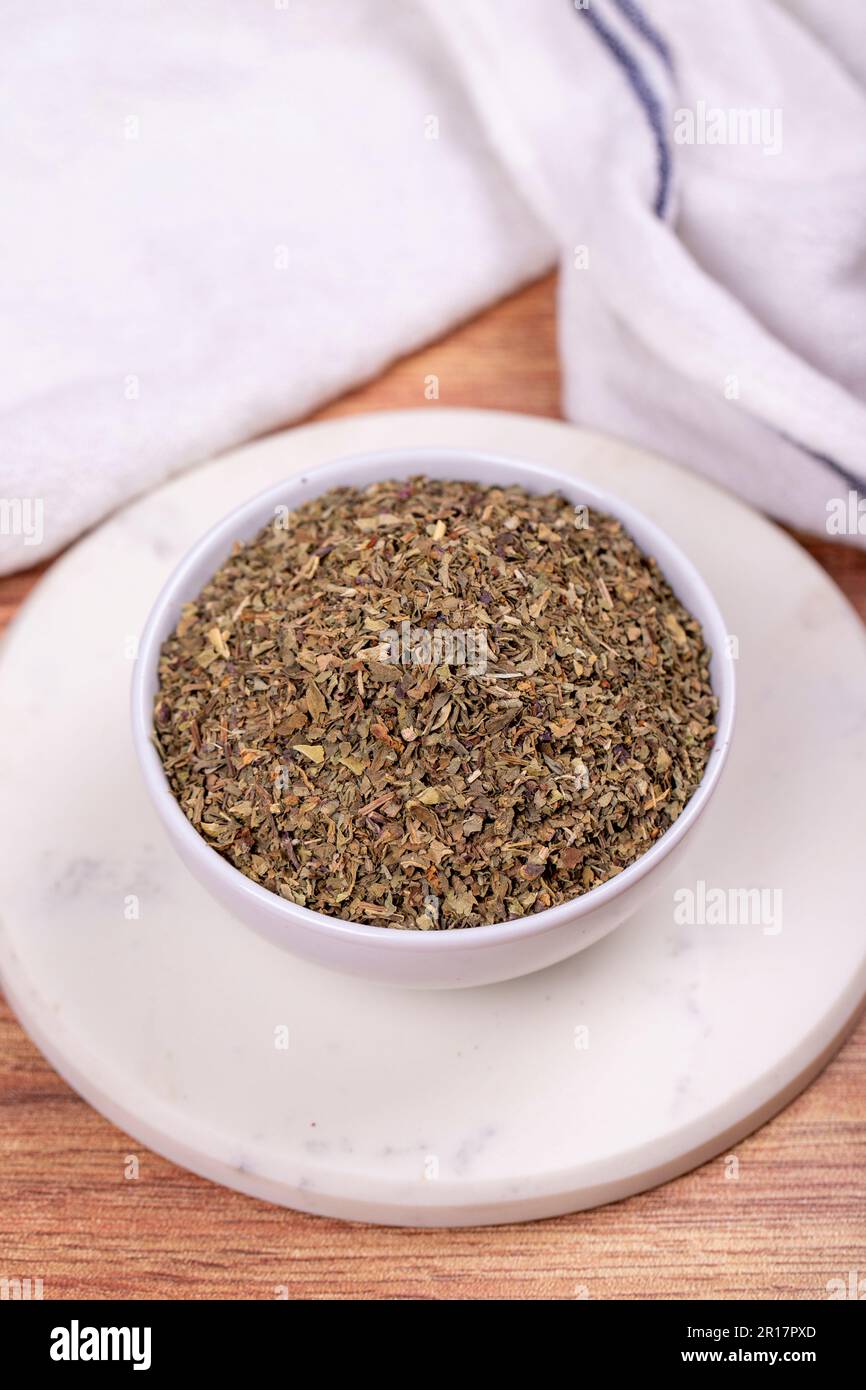 Dried crushed basil on wooden background. Dried ground basil powder ...