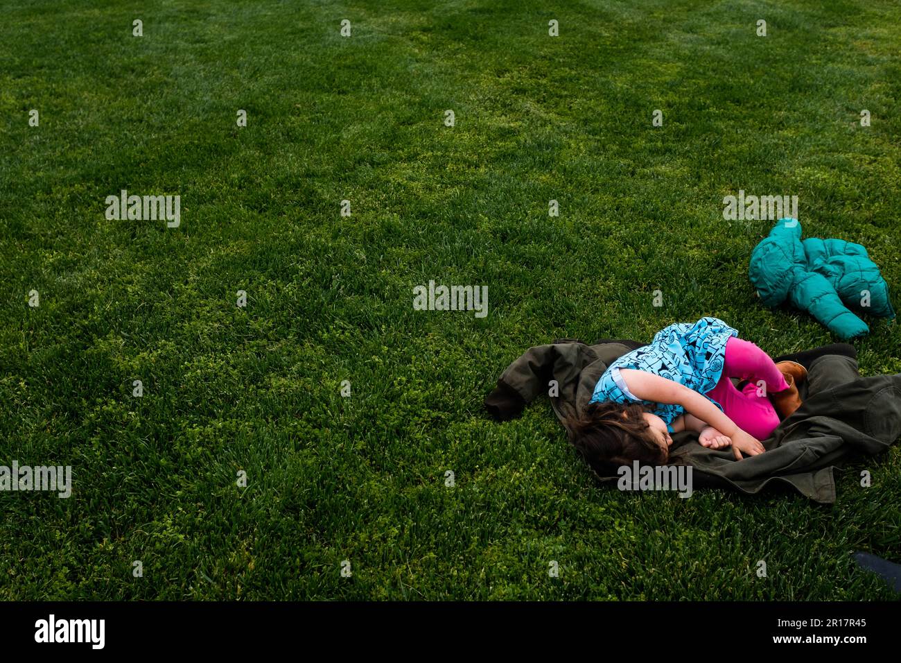 Little girl laying on a jacket in the grass Stock Photo - Alamy