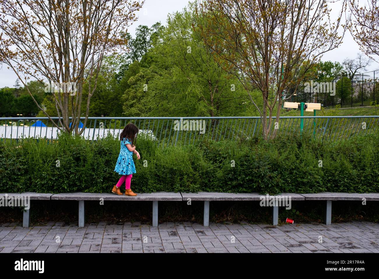Little girl walking on a park bench Stock Photo - Alamy