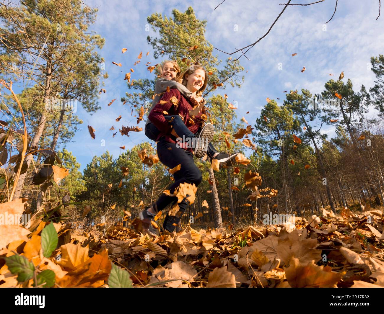 Teenage girl carrying sister piggyback running in forest Stock Photo ...